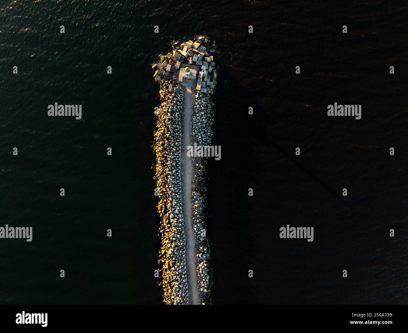 An aerial perspective shows a narrow pier lined with boulders ...