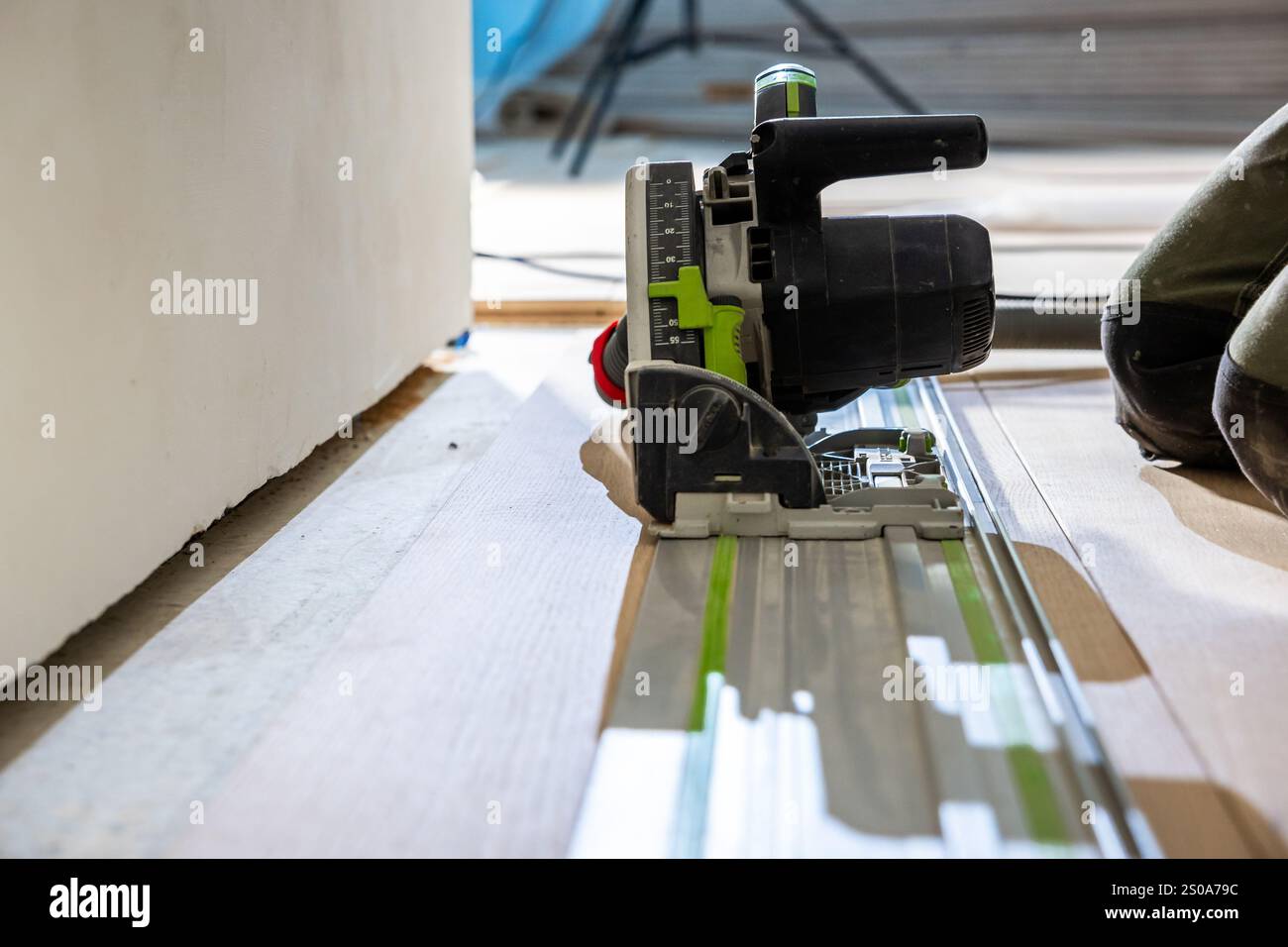 A track saw cuts through wood flooring on a guide rail at an indoor ...