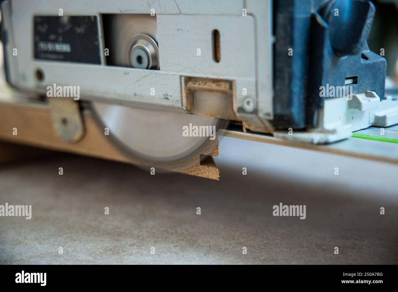 A circular saw blade cuts through wood, producing shavings. The focus ...