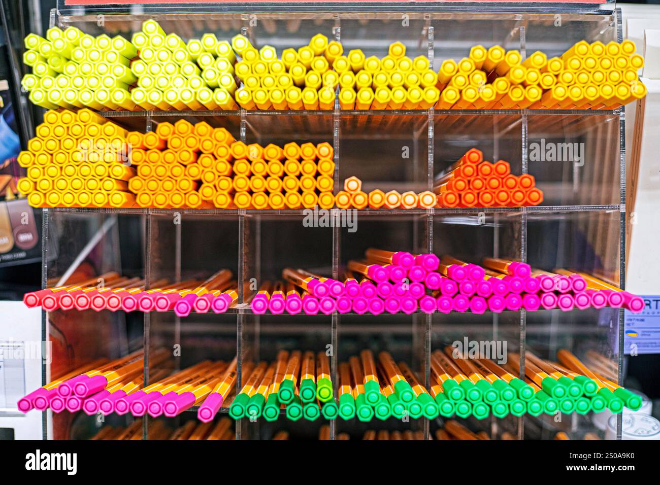 multicolored pens and liners arranged in cells on a shelf by color ...