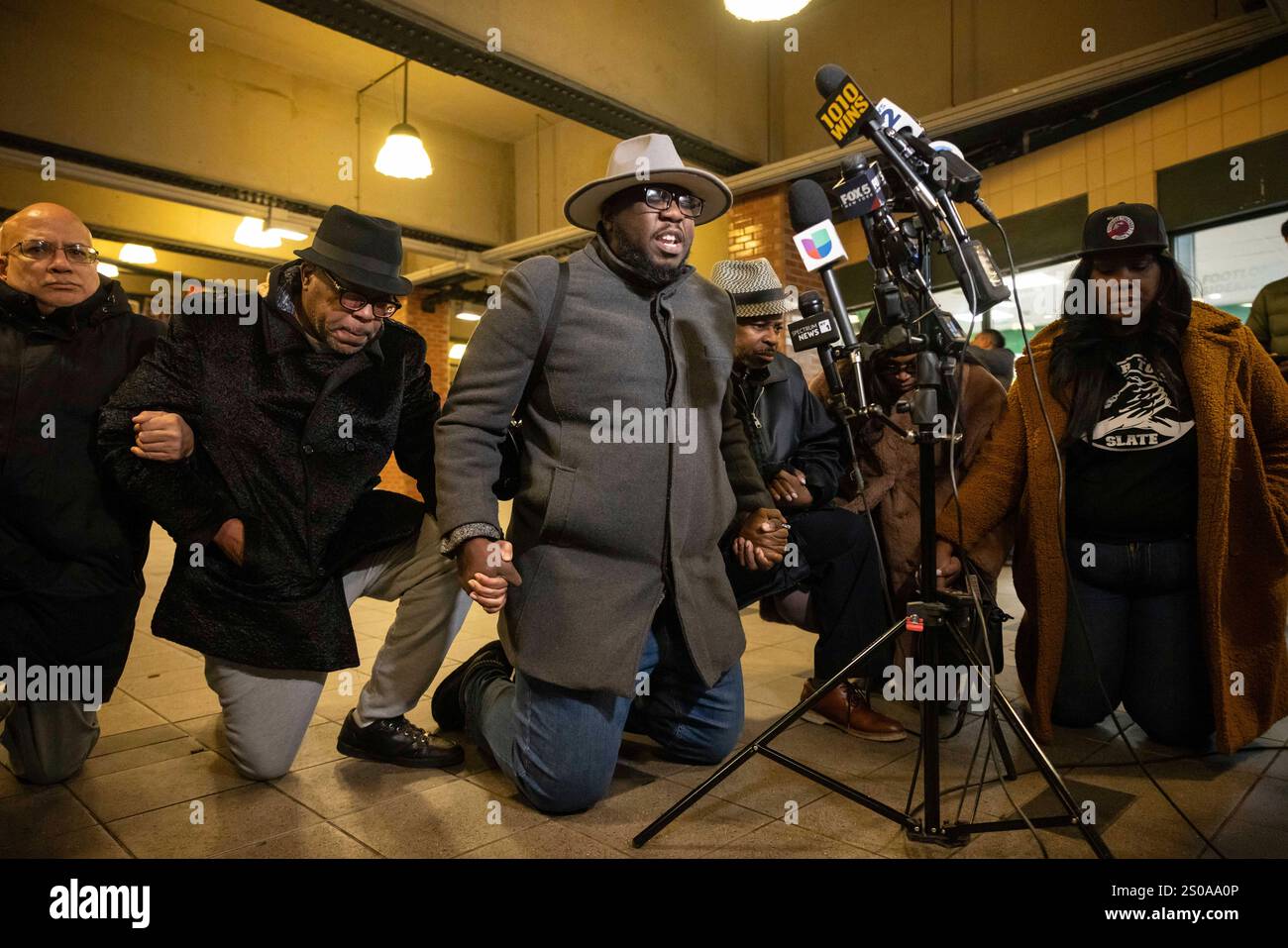 Rev. Kevin McCall, center, and community leaders pray during a press ...