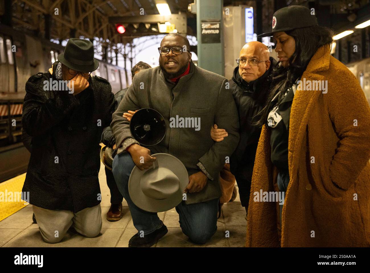 Rev. Kevin McCall, center, and community leaders pray on the F train ...