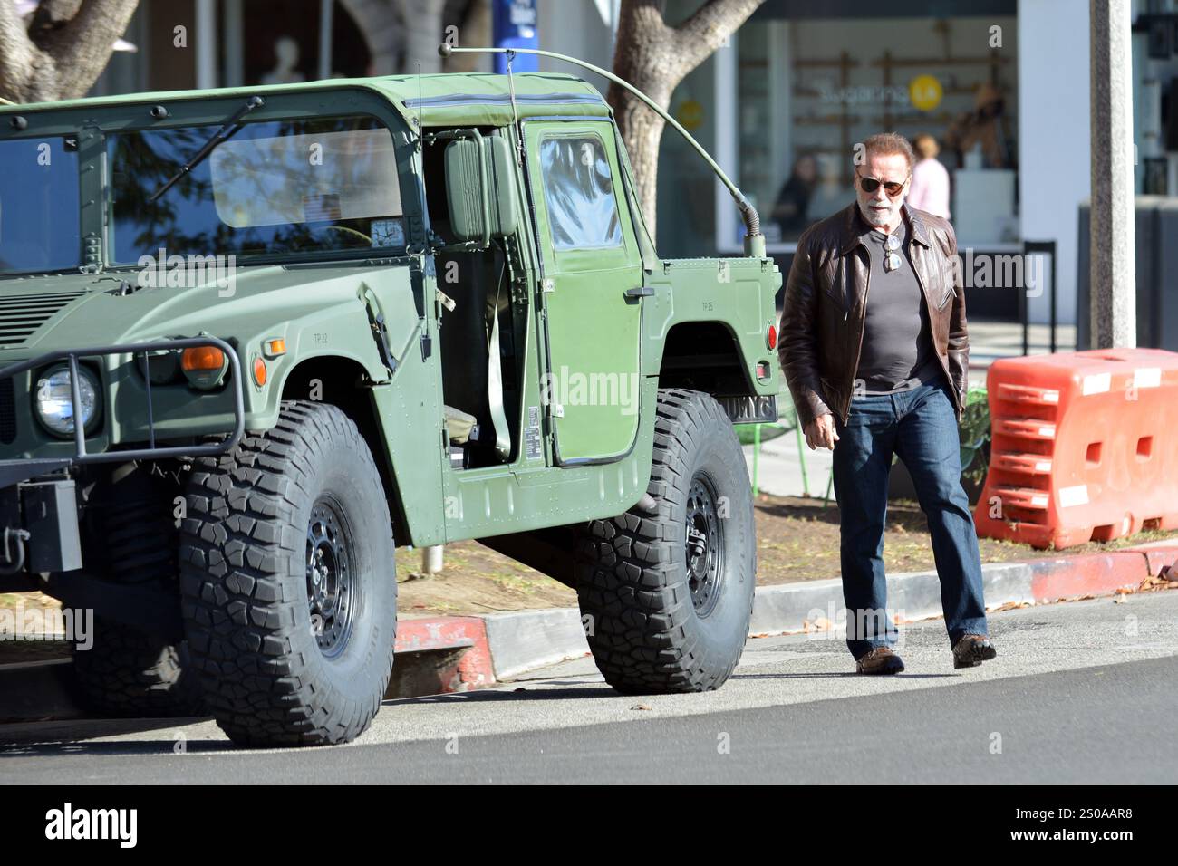 Arnold Schwarzenegger steps out of a rugged green Hummer, showcasing ...