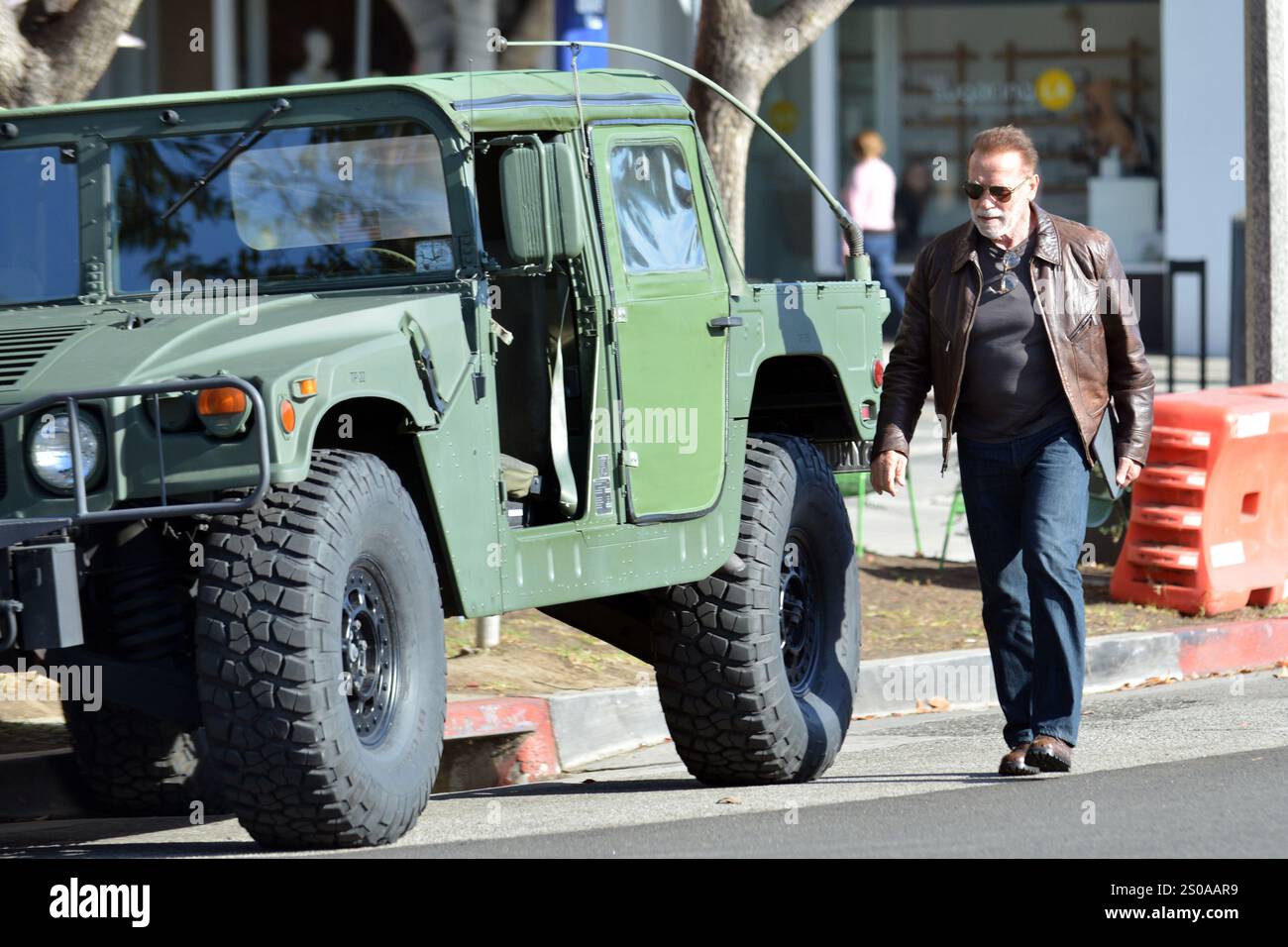 Arnold Schwarzenegger steps out of a rugged green Hummer, showcasing ...