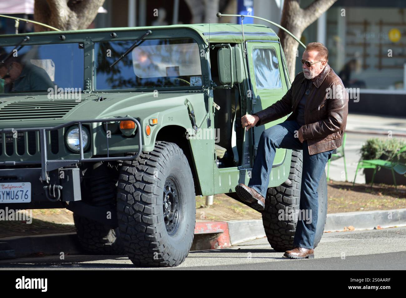 Arnold Schwarzenegger steps out of a rugged green Hummer, showcasing ...