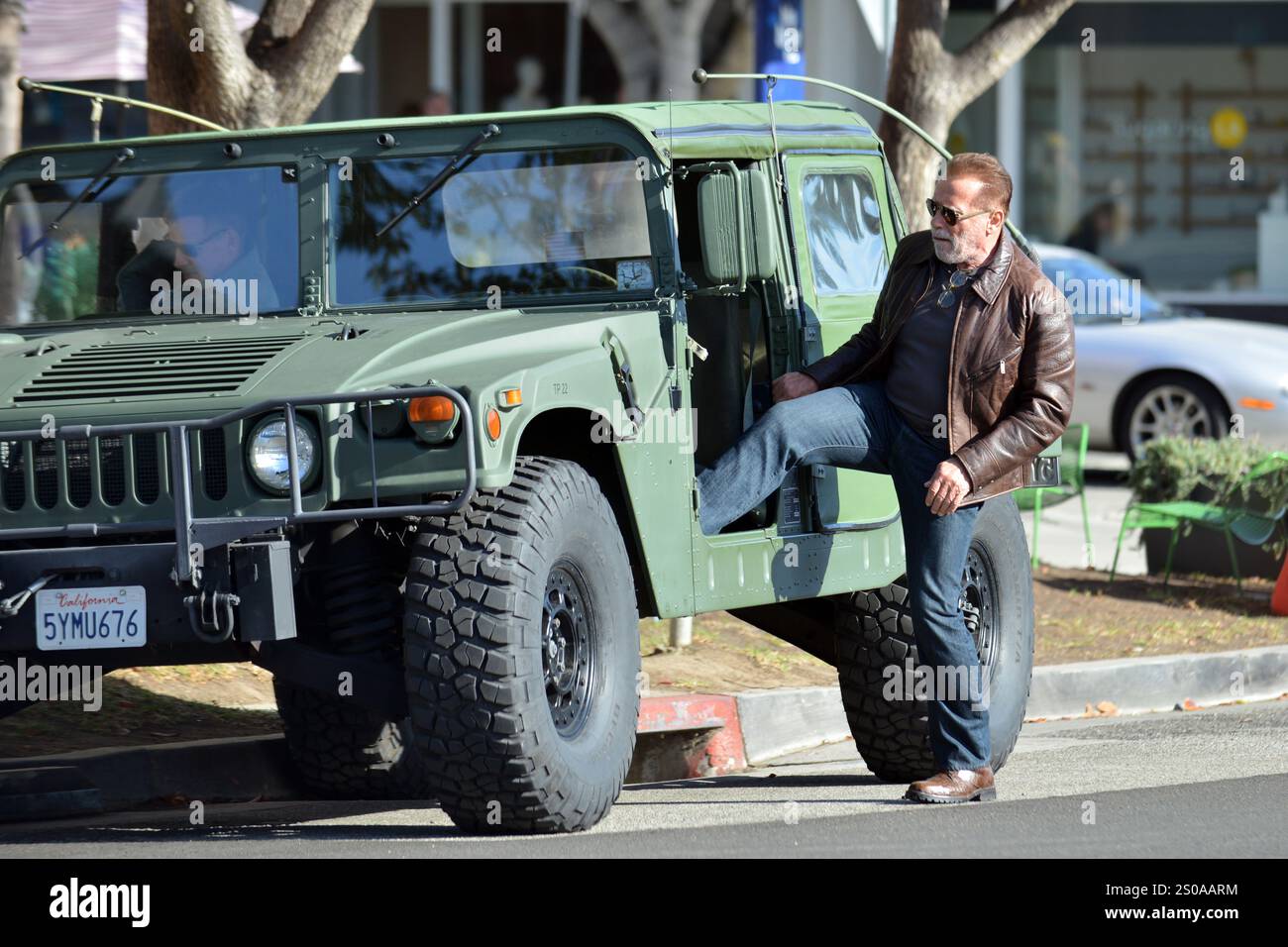 Arnold Schwarzenegger steps out of a rugged green Hummer, showcasing ...