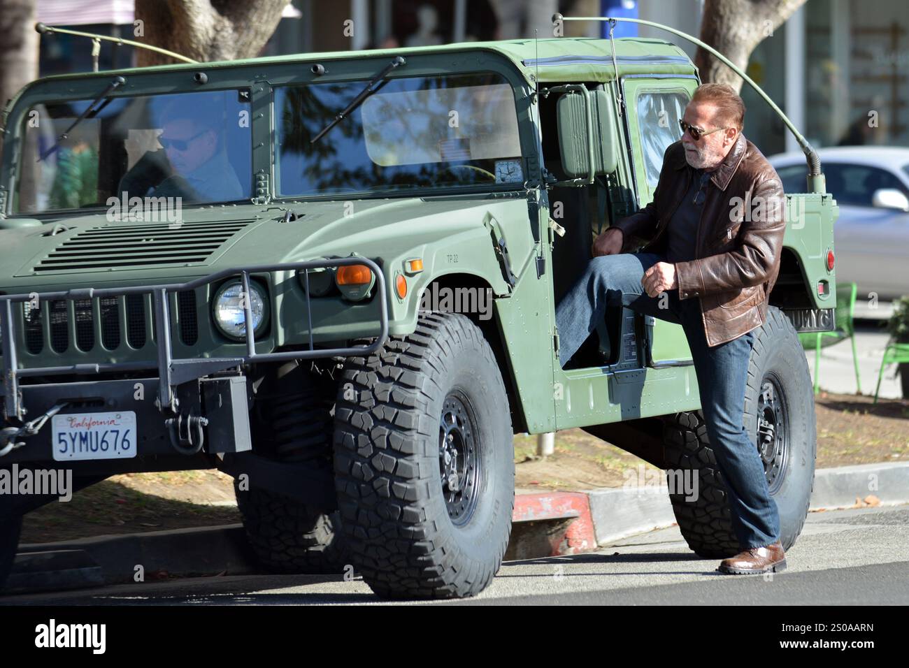 Arnold Schwarzenegger steps out of a rugged green Hummer, showcasing ...