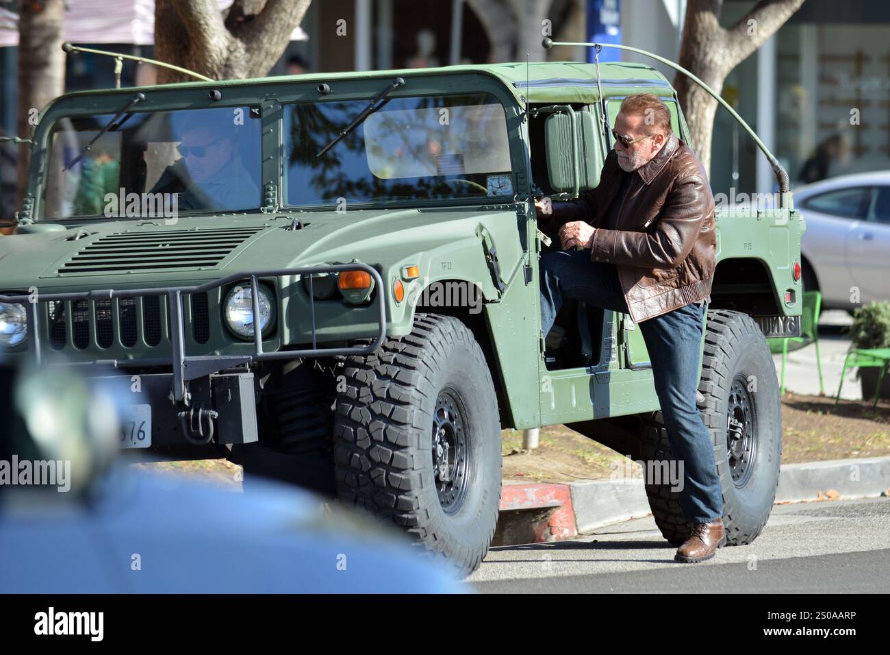 Arnold Schwarzenegger steps out of a rugged green Hummer, showcasing ...