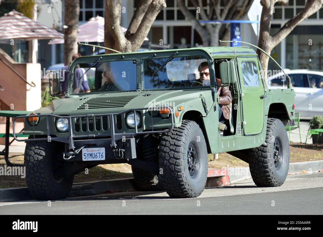 Arnold Schwarzenegger steps out of a rugged green Hummer, showcasing ...