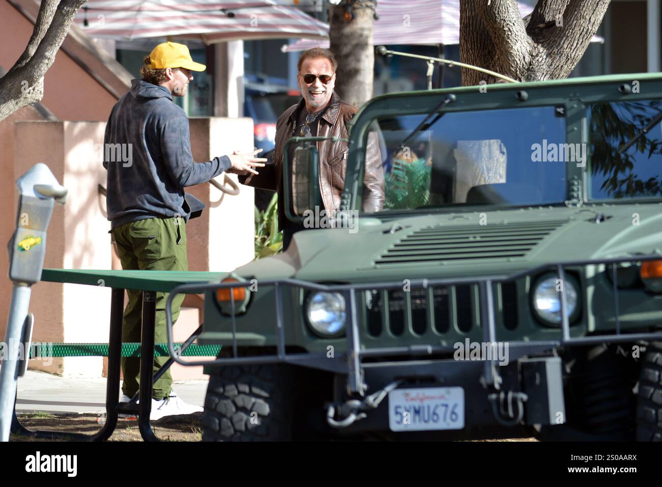 Arnold Schwarzenegger steps out of a rugged green Hummer, showcasing ...