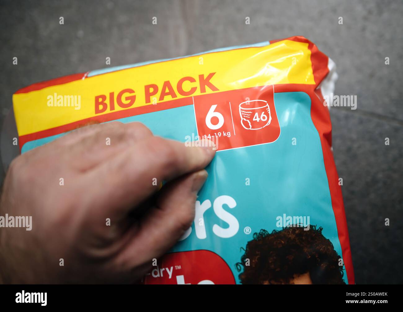 Paris, France - Mar 18, 2023: Hand pointing to a package of diapers ...