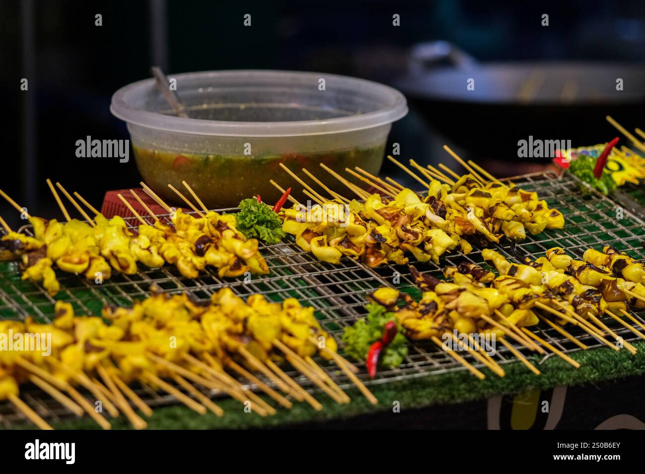 Grilled squid skewers on display at a vibrant Thai market Stock Photo - Alamy