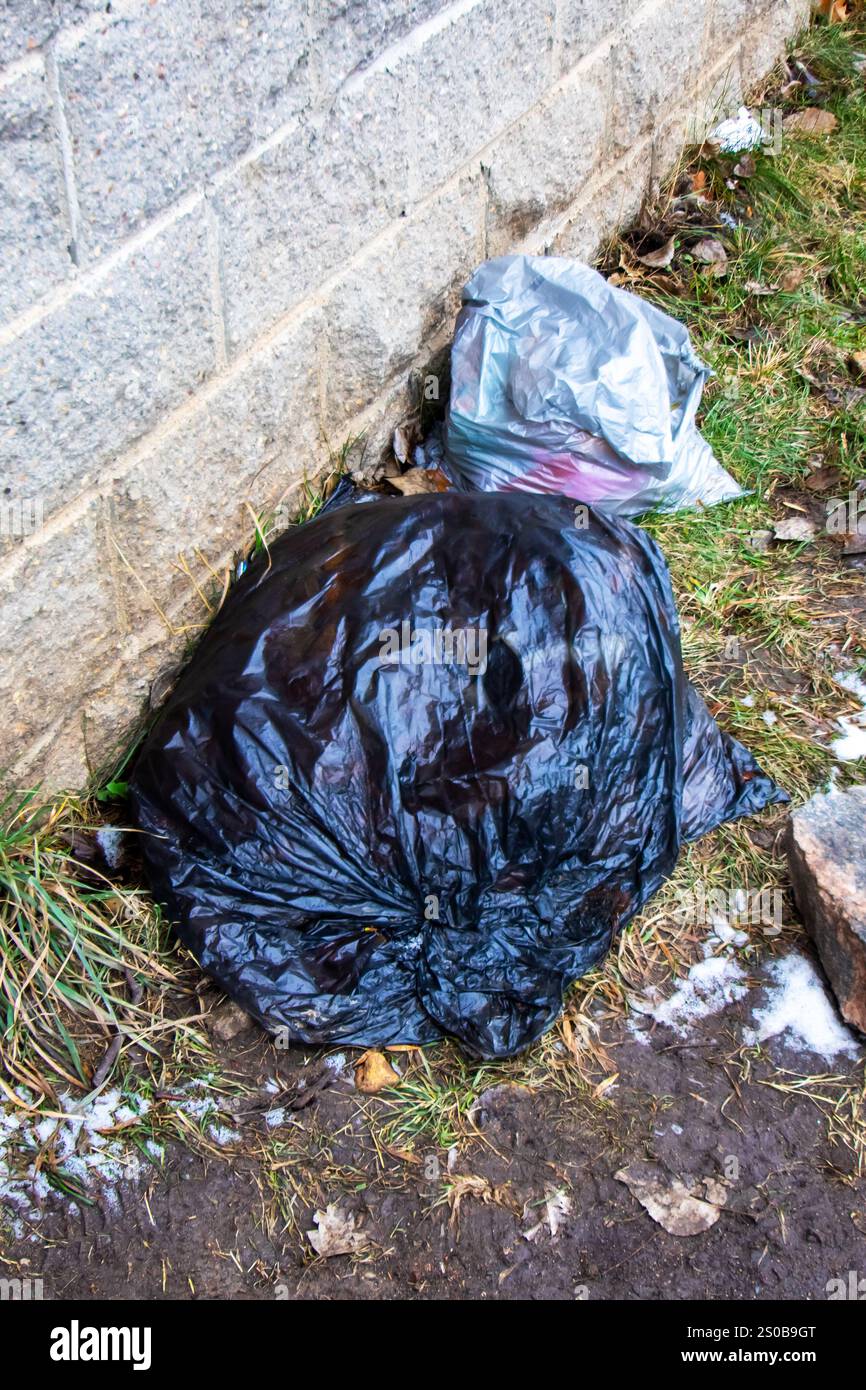 A large black garbage bag is resting against a wall, which highlights ...