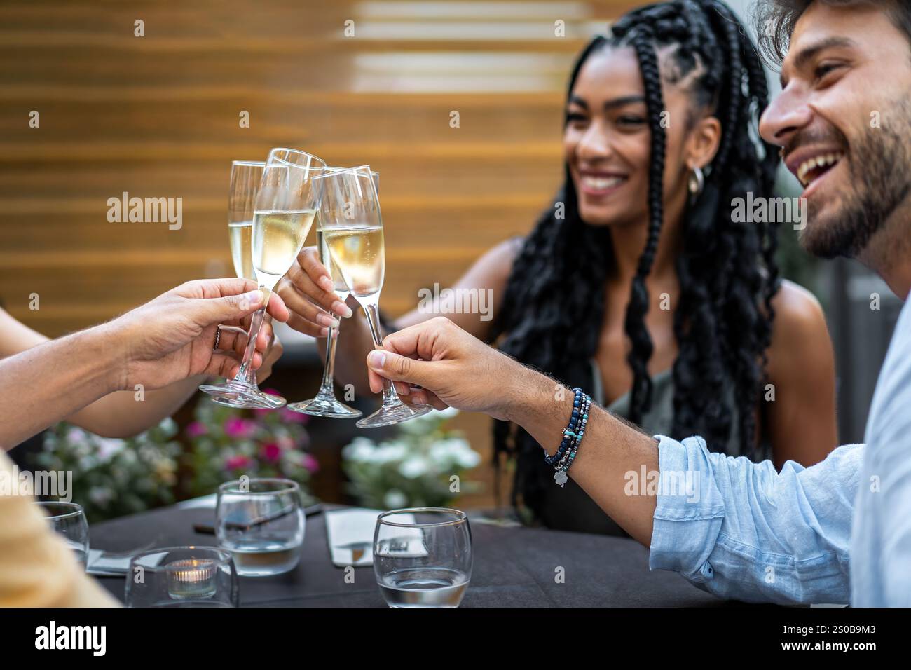 A joyful group of friends toasting with champagne glasses at an outdoor ...