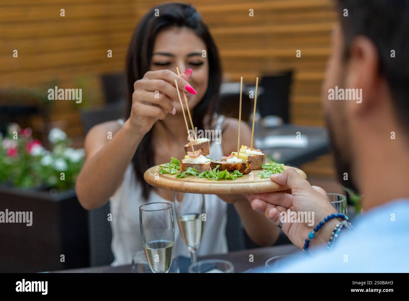A close-up of a woman picking food from a shared platter during an ...