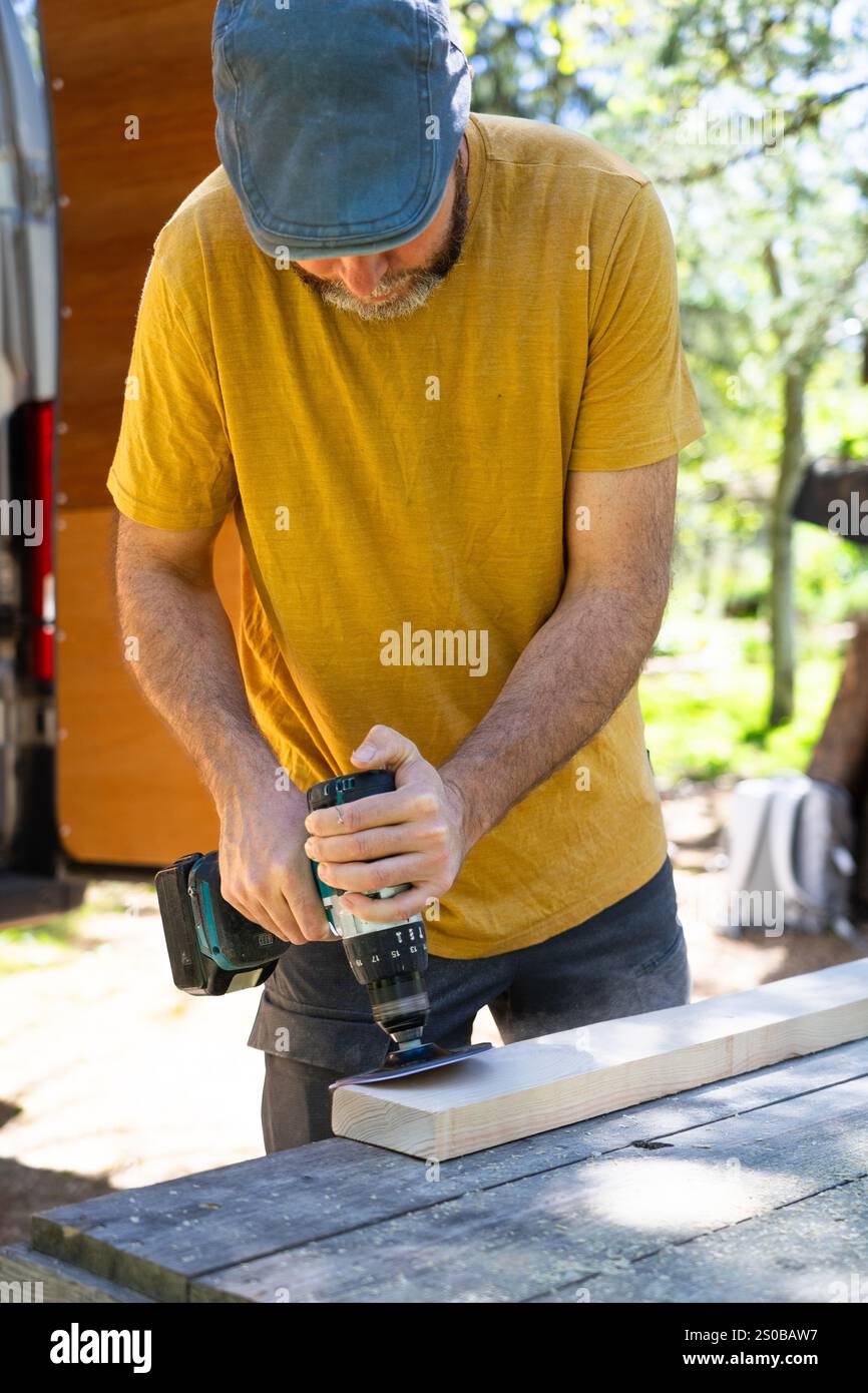 Carpenter sands wood with an orbital sander attachment on cordless ...