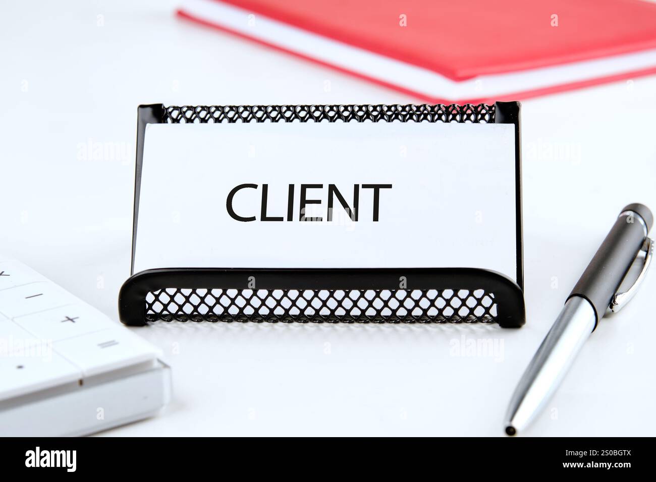 A business card holder displaying the word client sits on a desk ...