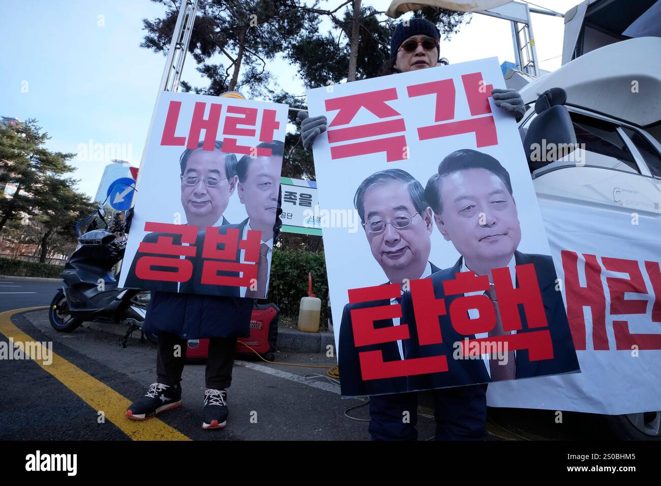 Protesters hold banners showing images of impeached President Yoon Suk ...