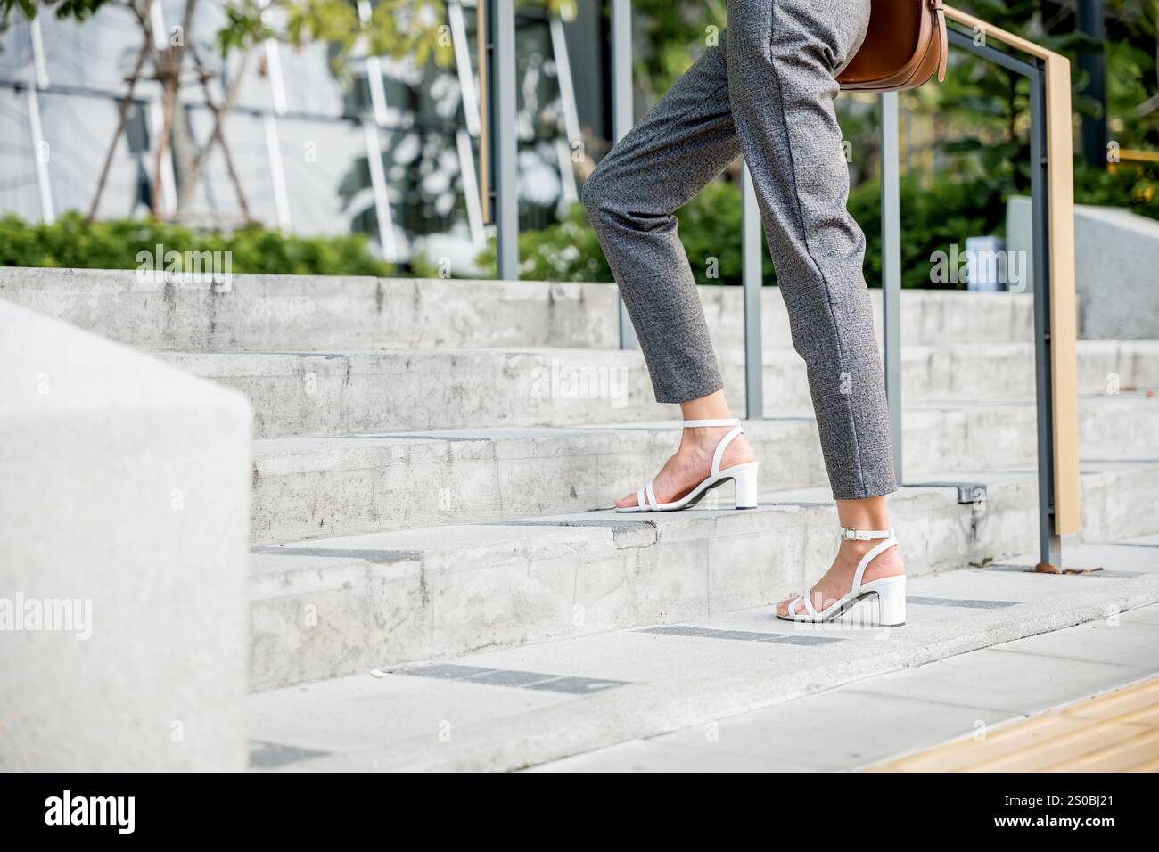 A businesswoman, portrayed from behind, races up the office stairs, her ...