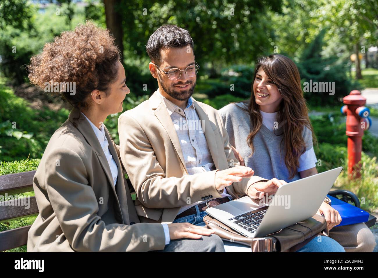 Group of young business people sitting on the bench outside office ...