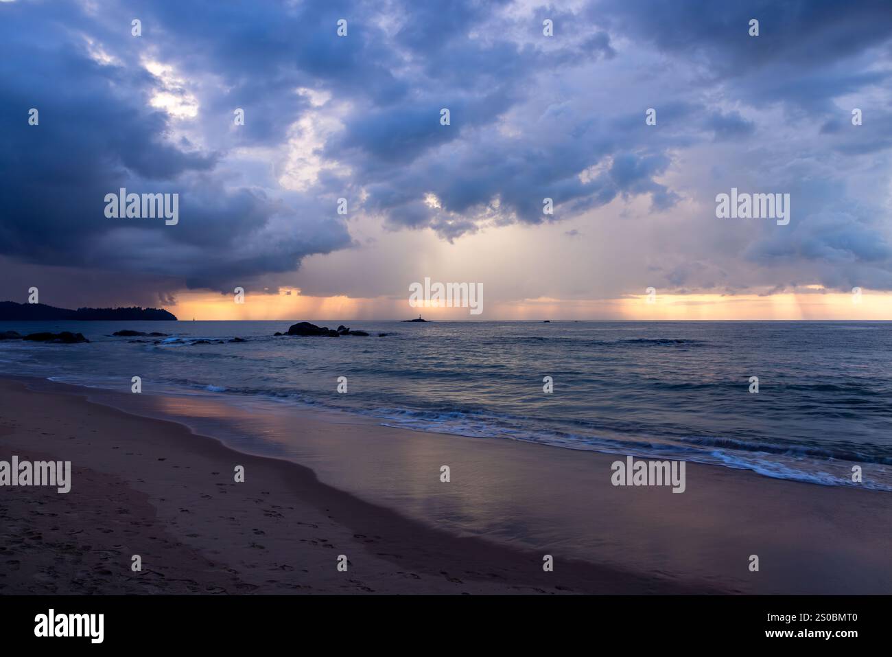 Sunset at the shoreline in Khao Lak, Thailand. Rain at the horizon ...