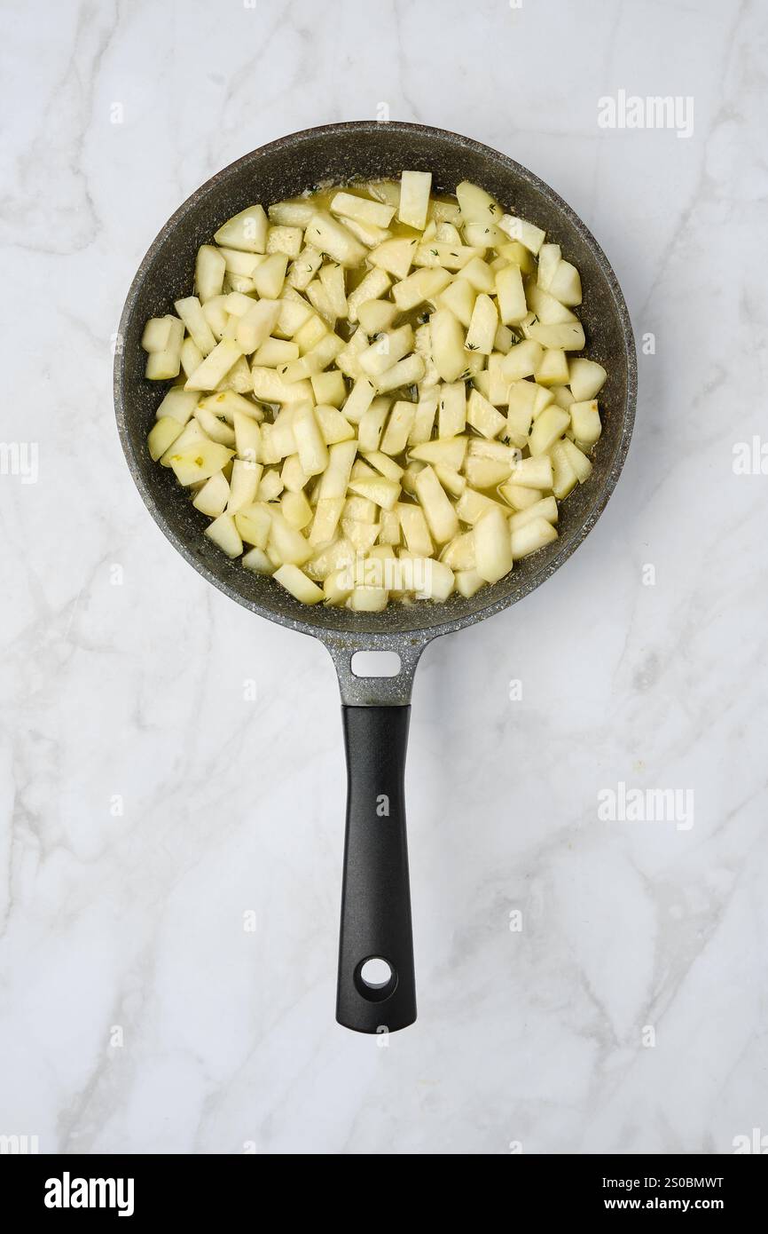 Green pears are cut into small pieces and placed in a frying pan. The ...