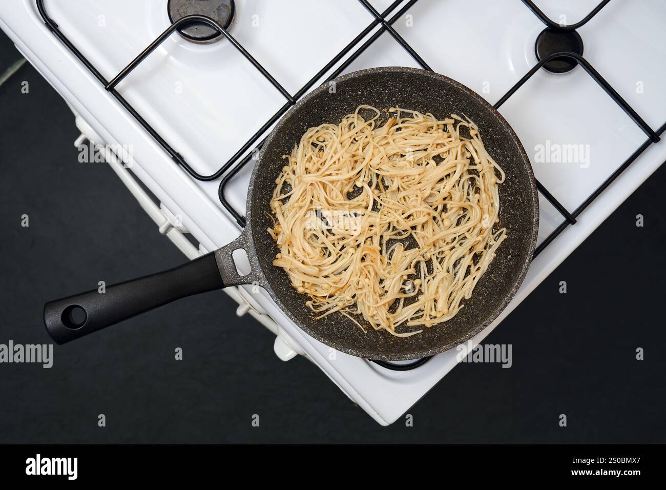 Overhead view of a frying pan with golden-brown enoki mushrooms on a ...