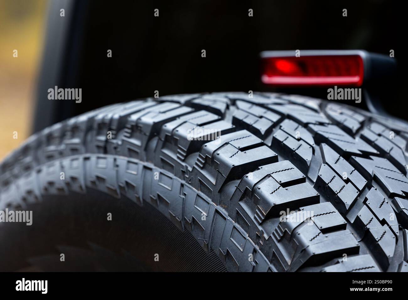 Deep tread of a new off road tire mounted on the rear door of an off ...