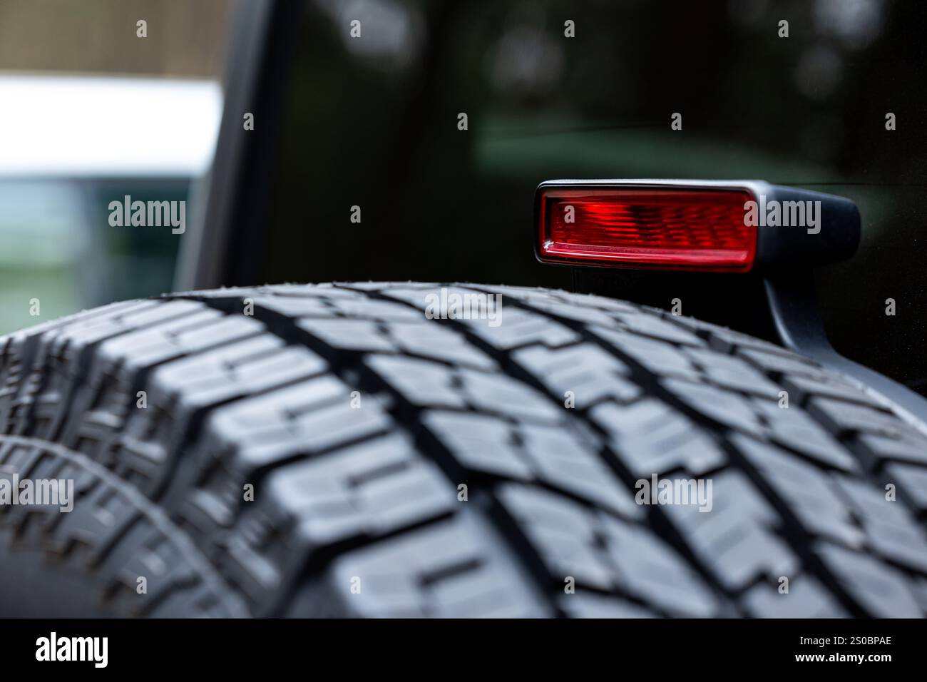 Deep tread of a new off road tire mounted on the rear door of an off ...