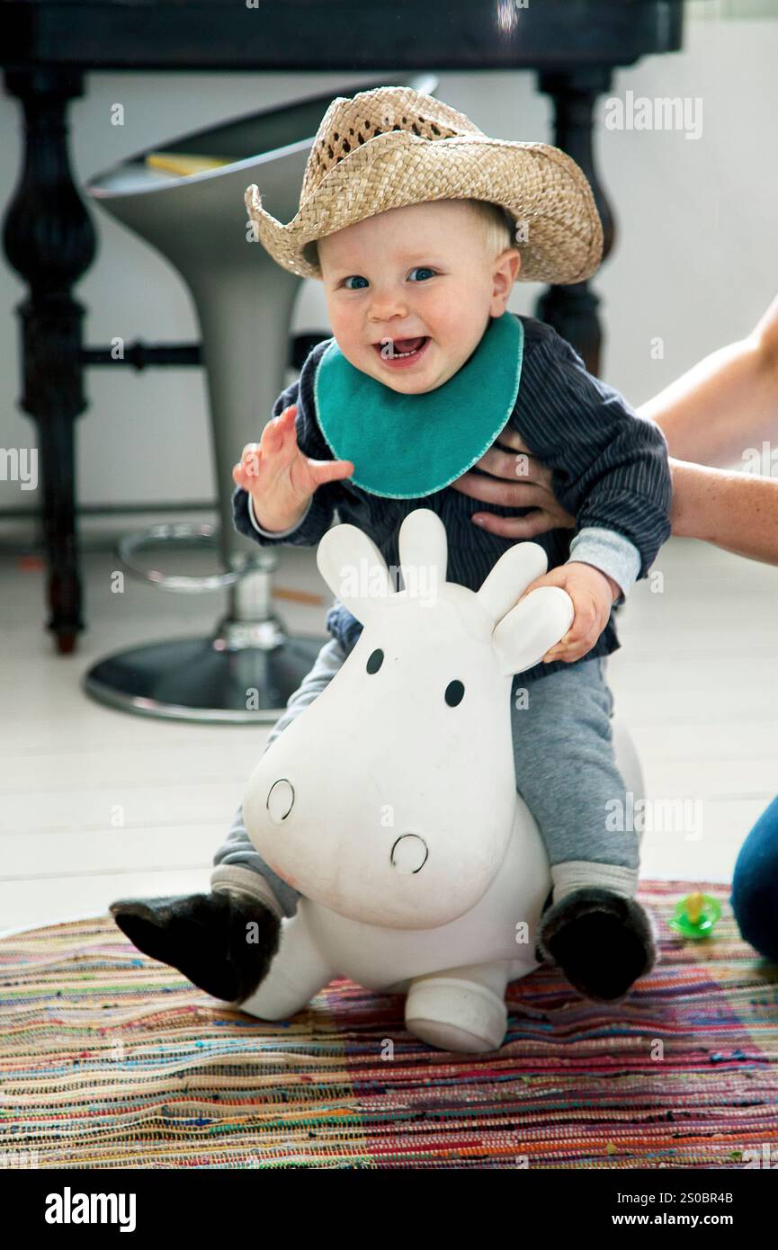 Baby with cowboyhat riding a toy plastic cow Stock Photo - Alamy