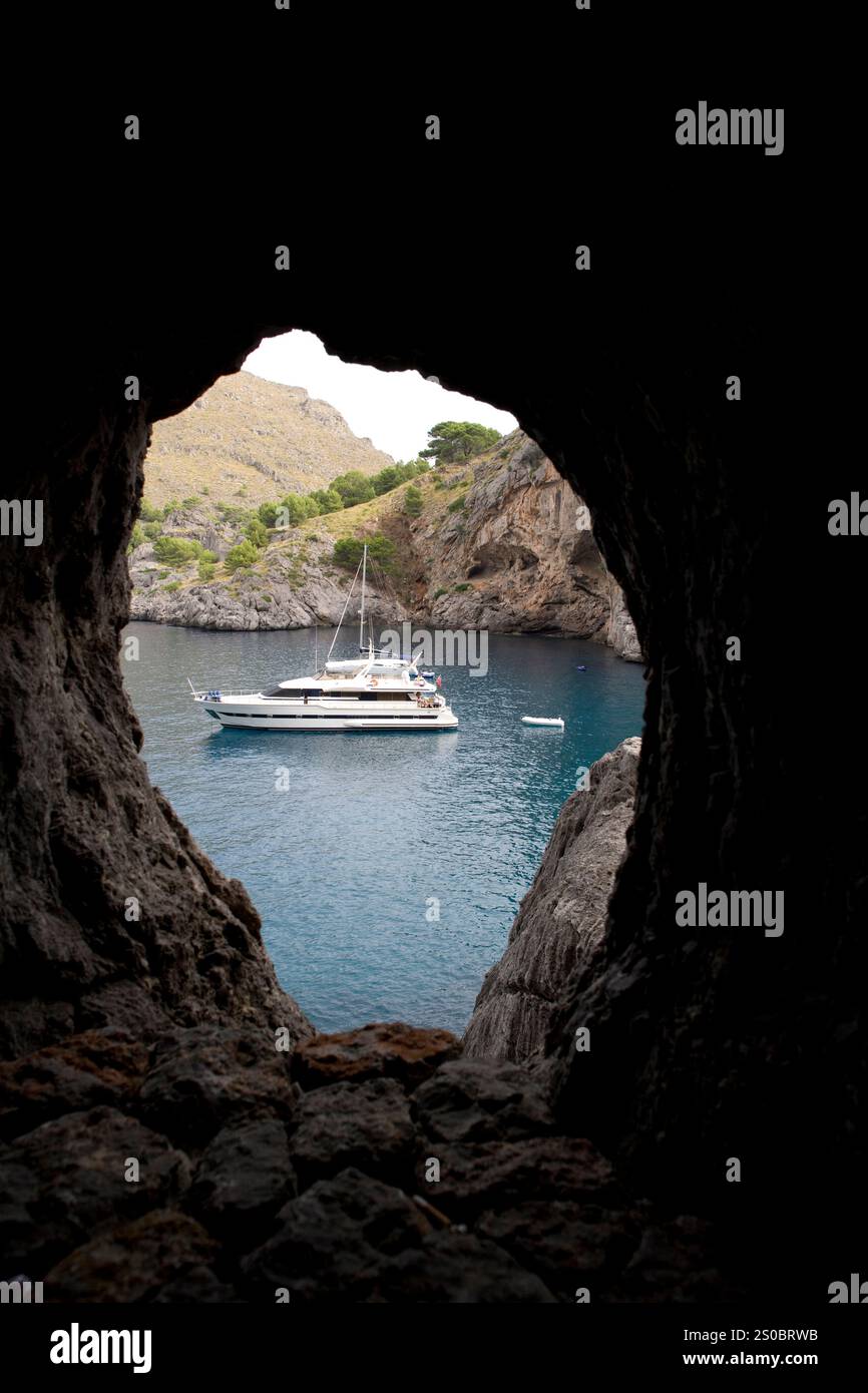 Yacht in cove, visible through hole in rock wall Stock Photo - Alamy