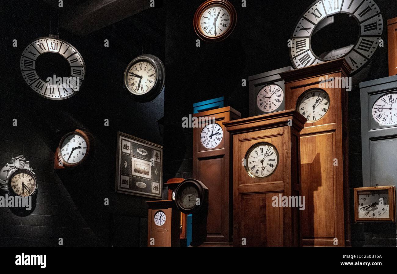 A collection of various clocks displayed on a dark wall, featuring ...