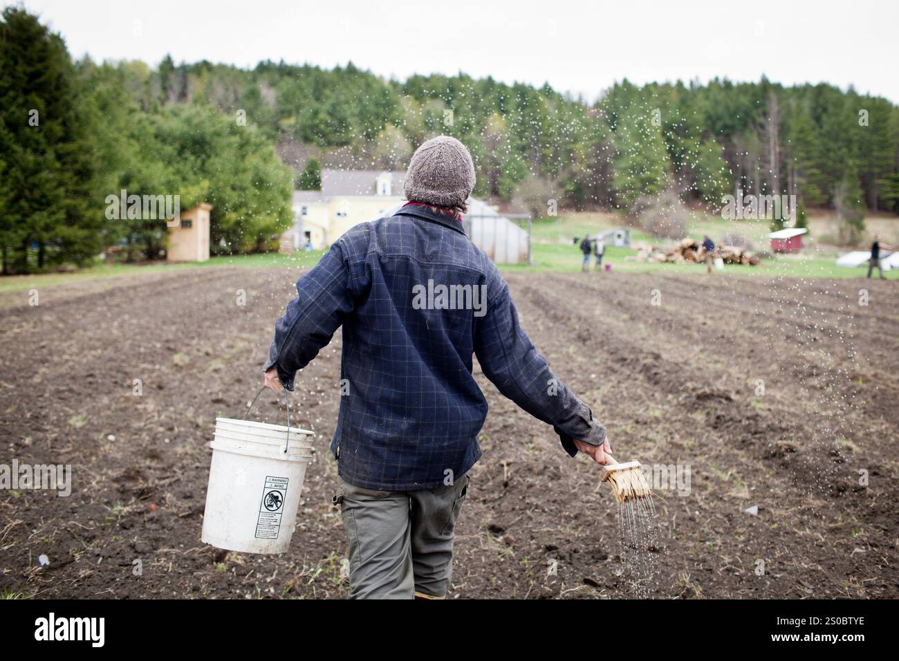 Farmer and bucket in bio dynamic farm field Stock Photo - Alamy