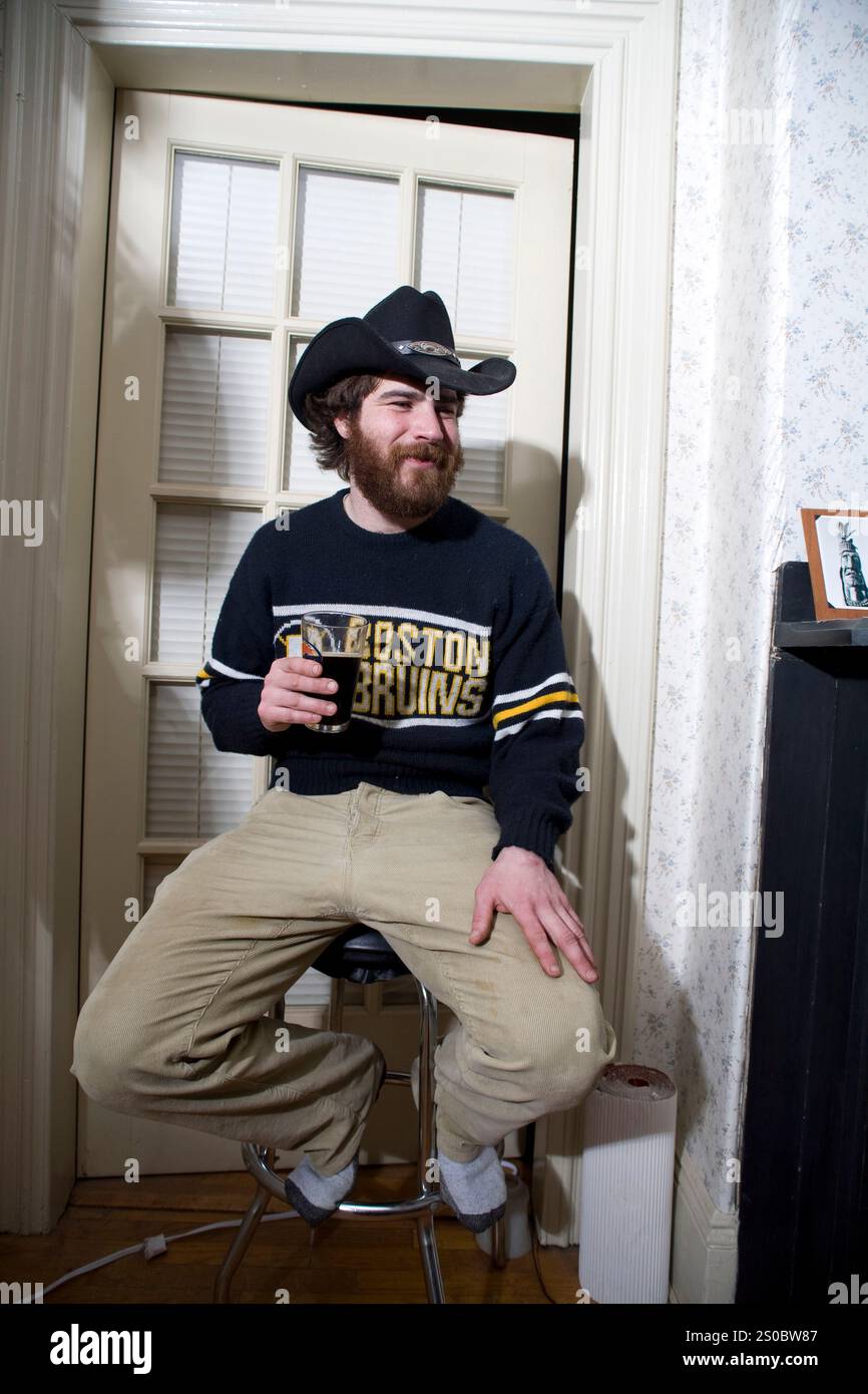 Young man with beard in a cowboy hat on stool in doorway Stock Photo ...