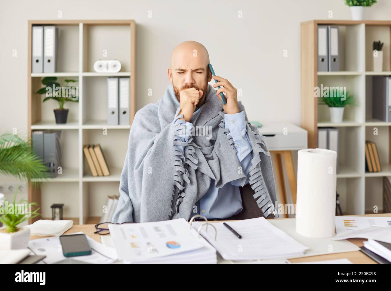 Sick man sitting at desk coughing working answering phone call, blowing ...