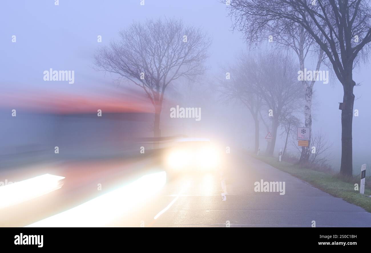 Saterland, Germany. 27th Dec, 2024. Car headlights dazzle on a road in ...