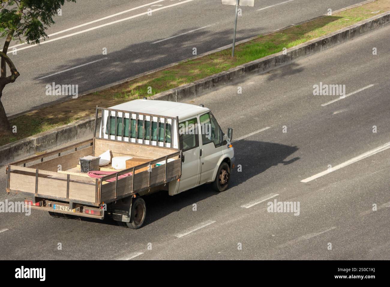 White ford transit dropside driving on highway with goods in the cargo ...