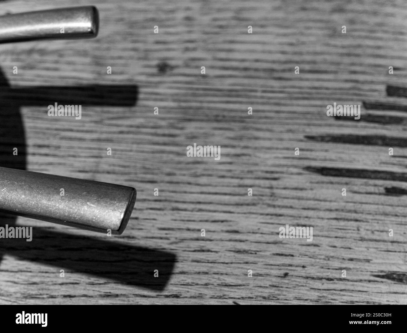 Two metal objects are on a wooden surface. One of the objects is bent ...