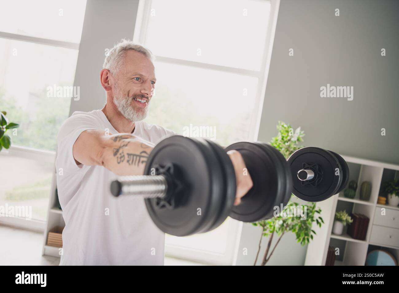 Elderly man lifting weights in a bright home gym showcasing active ...
