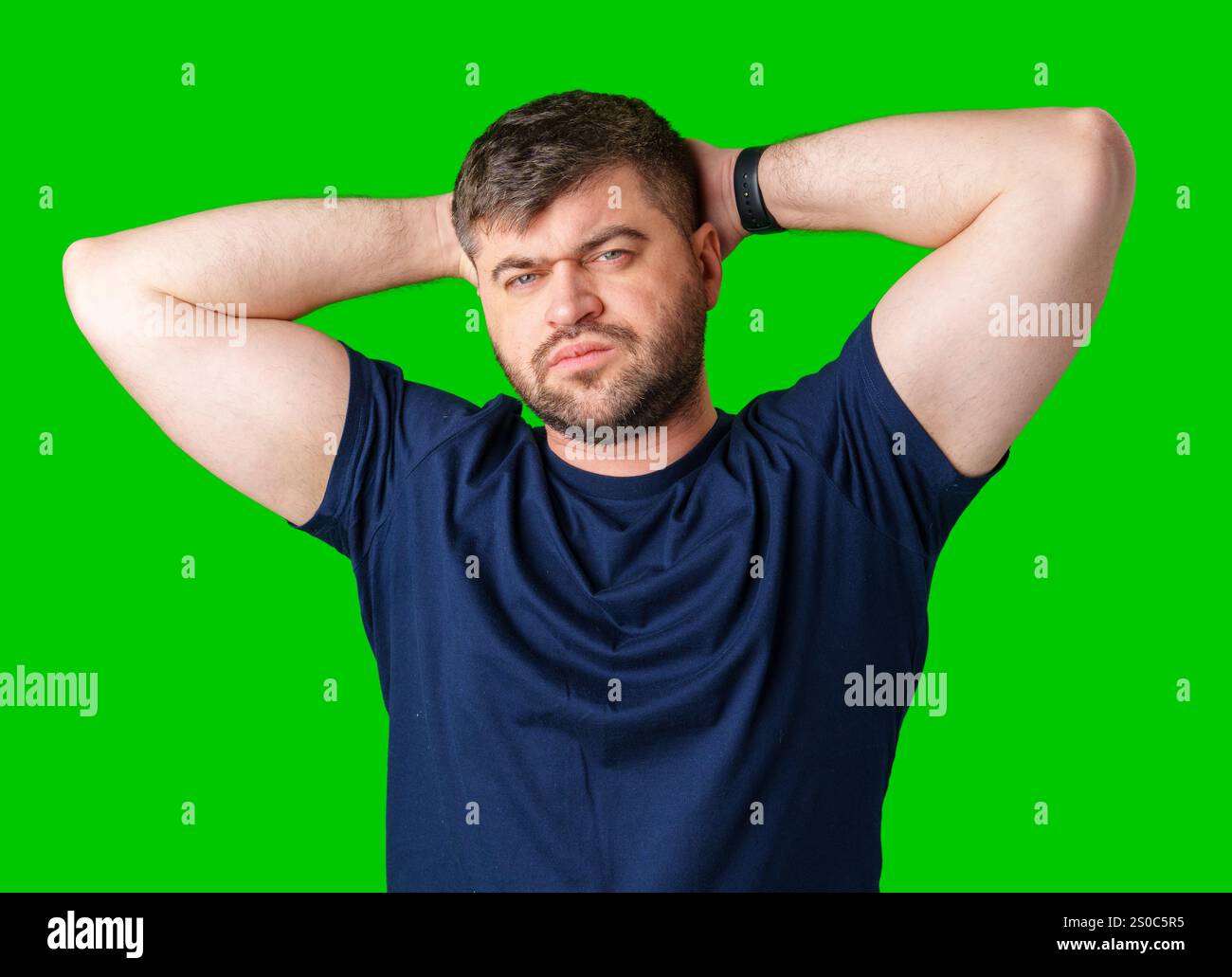 A man poses confidently with his hands behind his head against a bright ...