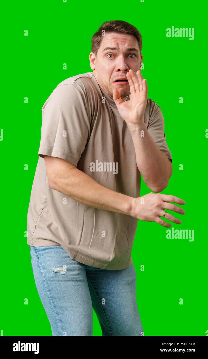 Man expressing fear while standing against a bright green background ...