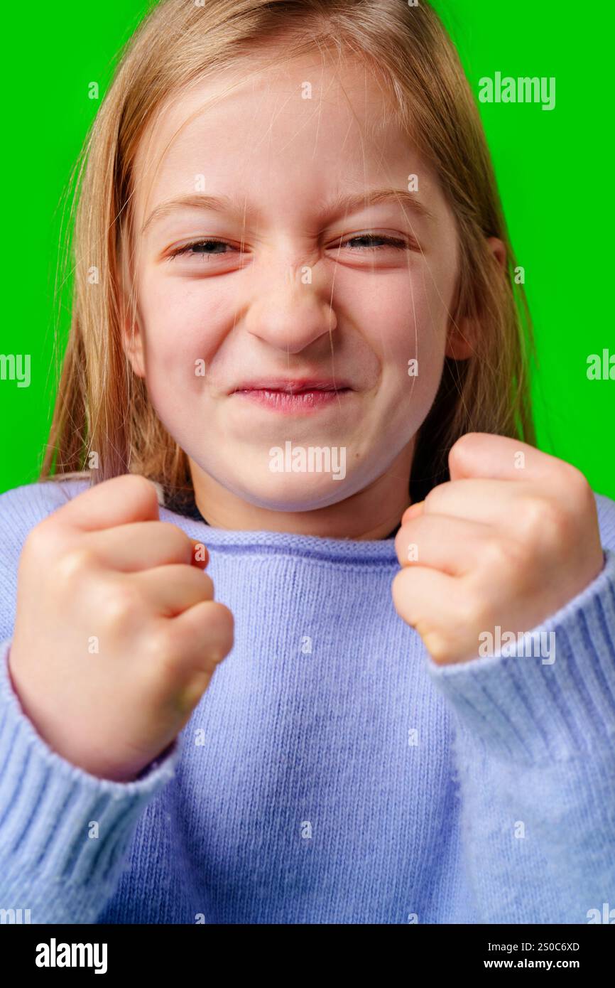 Young girl expressing determination with clenched fists against a ...