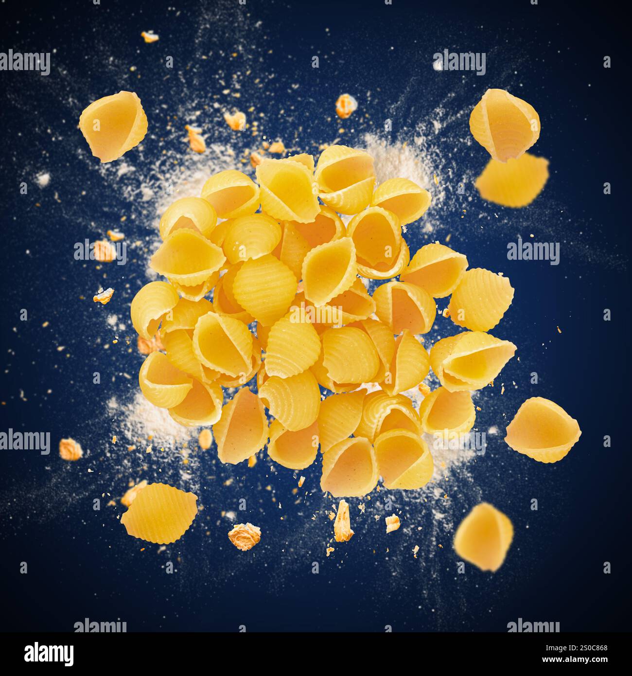 Raw conchiglie pasta shells exploding on a blue background, creating a ...