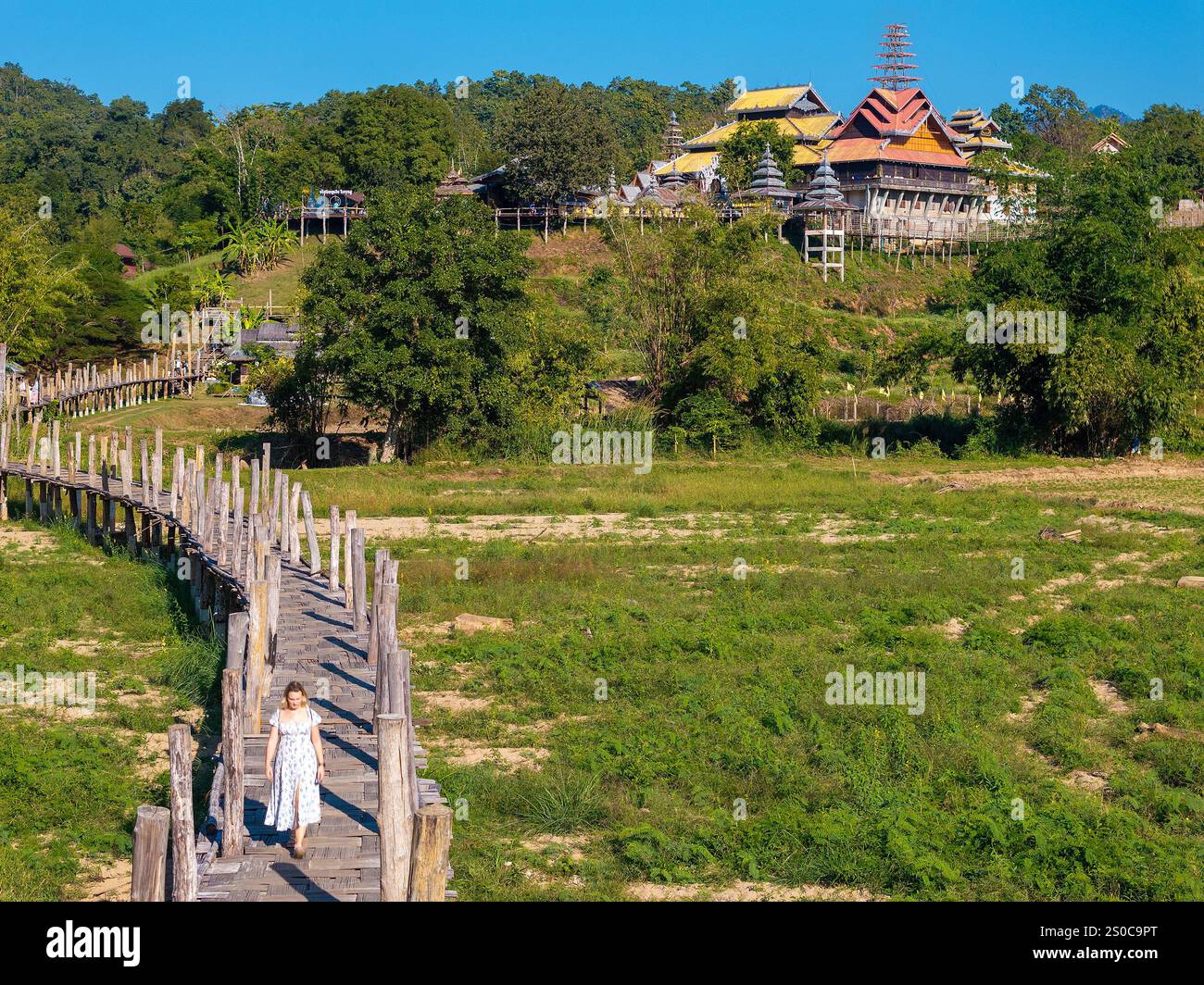 Aerial view of a young woman walking the Bamboo Bridge and Buddhist ...