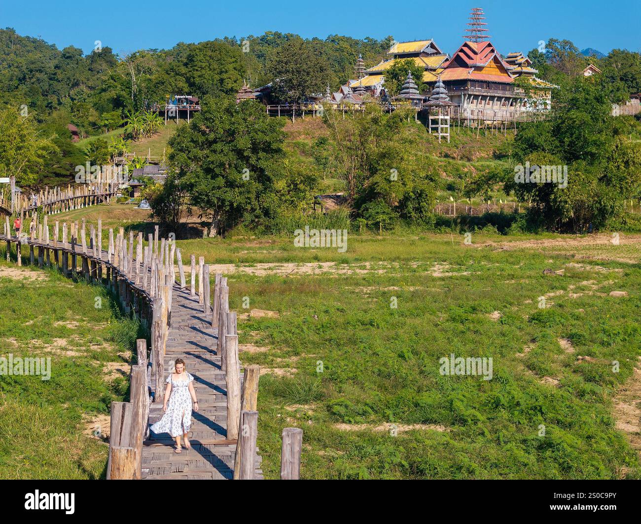 Aerial view of a young woman walking the Bamboo Bridge and Buddhist ...