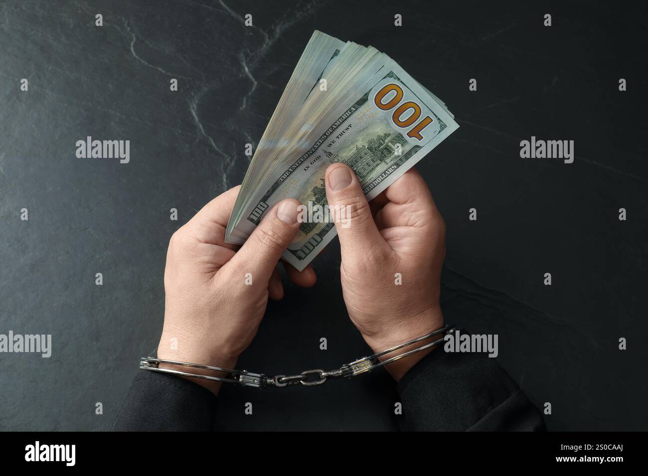 Corruption. Man in handcuffs holding dollar banknotes at grey textured ...
