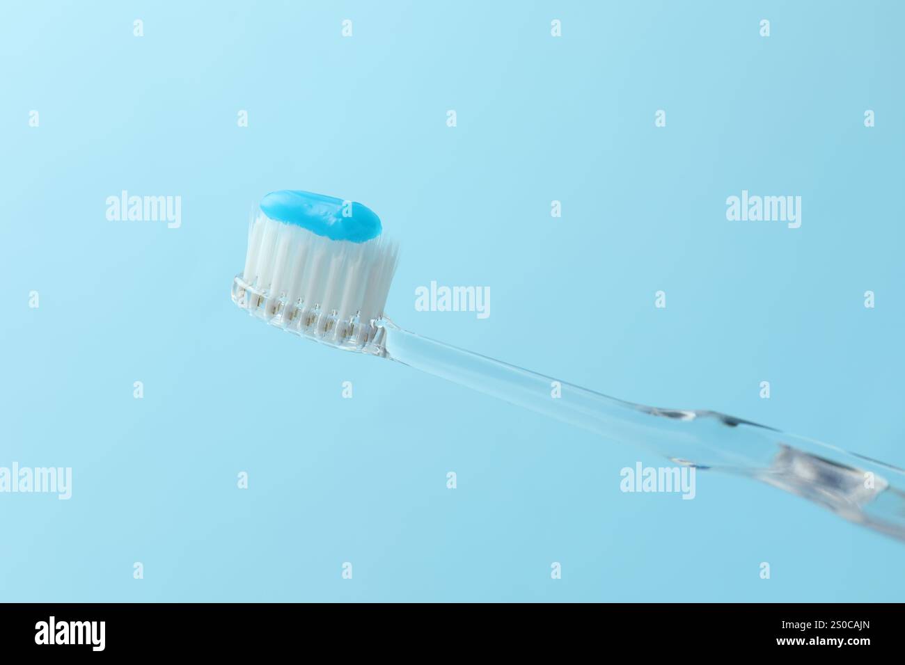Toothbrush with toothpaste in air on light blue background, closeup ...