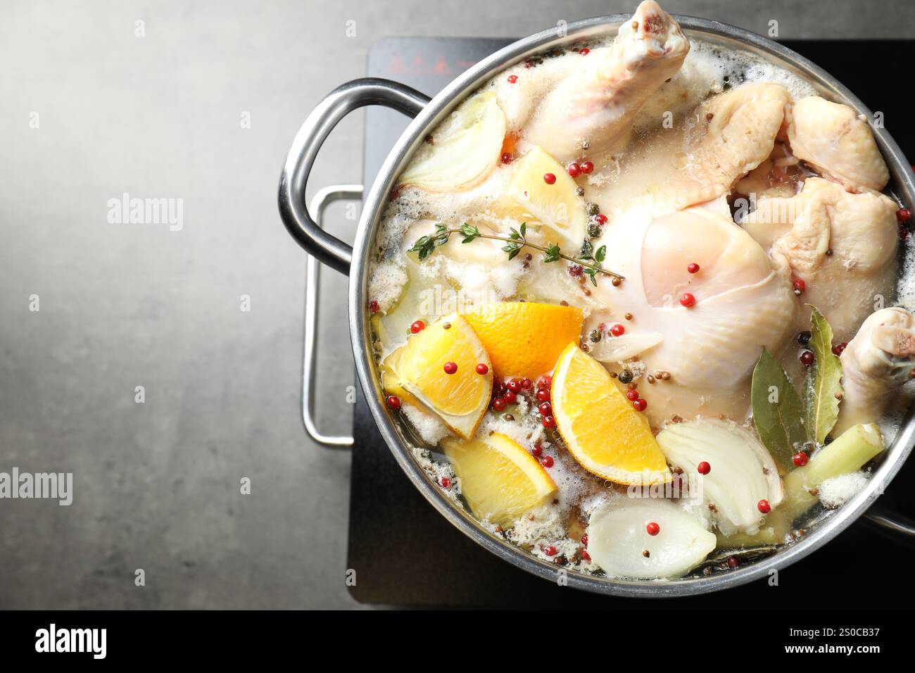 Whole fresh turkey, cut citrus fruits, thyme and spices boiling in pot ...