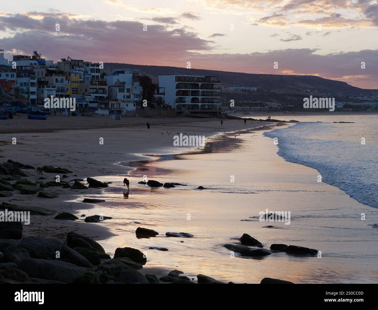Red sky at dawn over the village of Taghazout and with its sandy and ...
