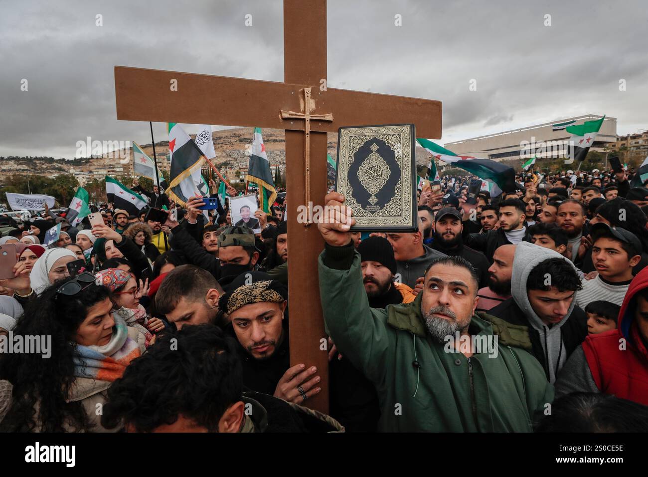 Syrians hold a copy of the Quran next to a Christian cross during a ...